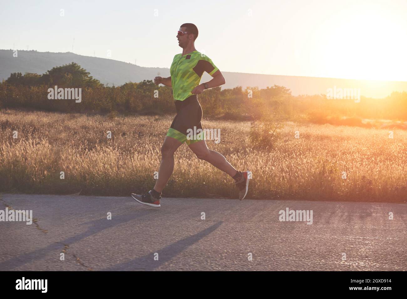 triathlon athlete running on morning training sunrise in the background ...