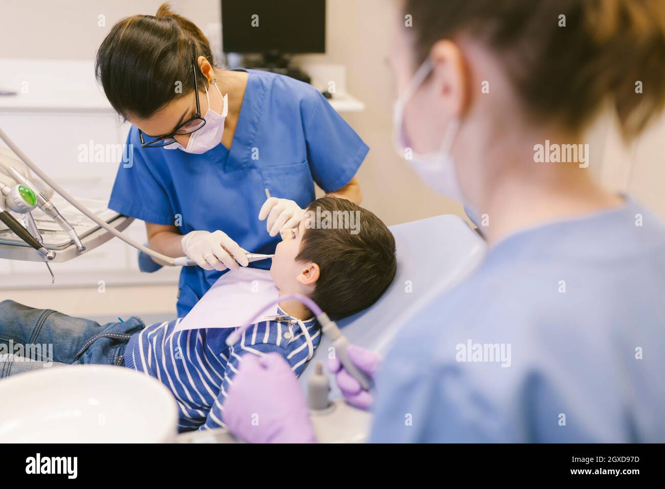 High angle of dentist and assistant treating teeth of boy during ...