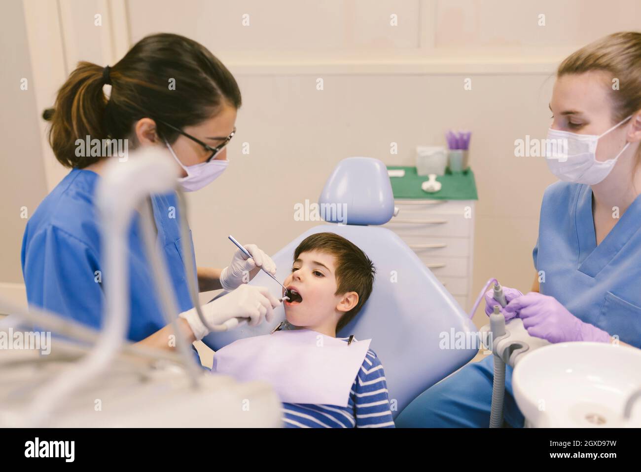 High angle of dentist and assistant treating teeth of boy during ...