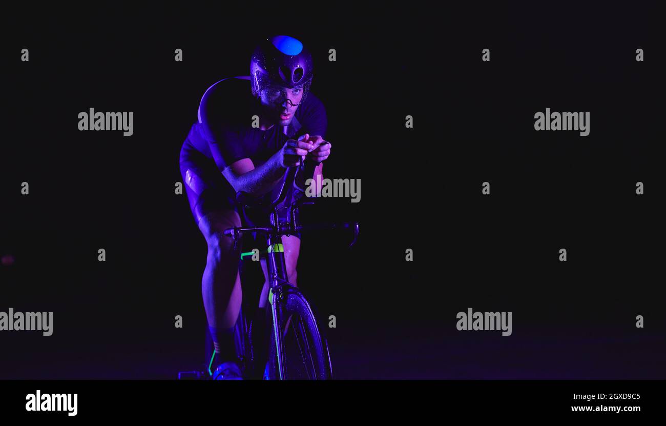 triathlon athlete cycling fast riding professional racing bike at night ...