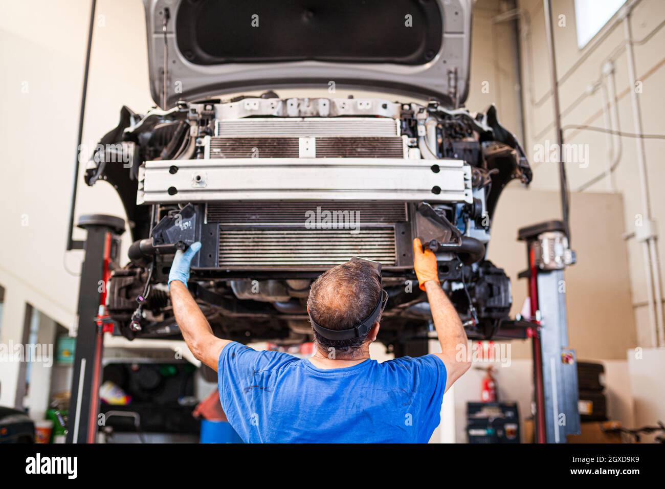 Back view of male mechanic in gloves fixing radiator of automobile ...