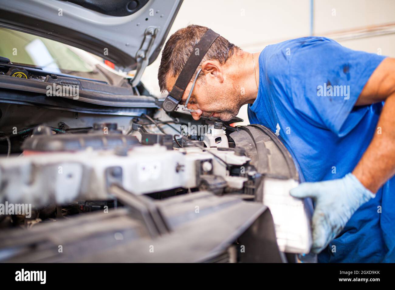 Side view of busy mature male technician fixing engine of broken car in ...