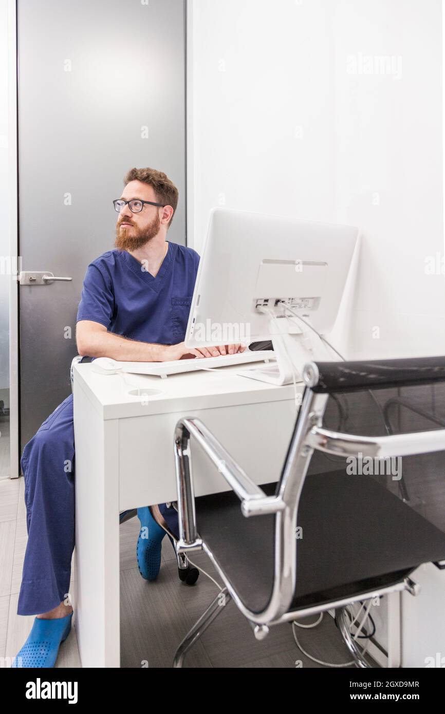 man in medical uniform typing on keyboard of computer while working in ...