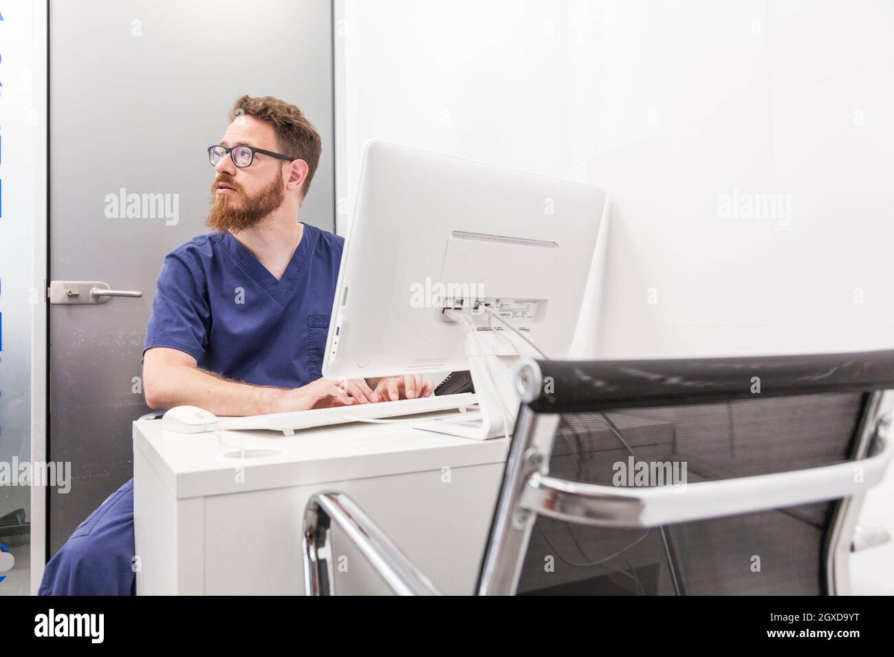 man in medical uniform typing on keyboard of computer while working in ...