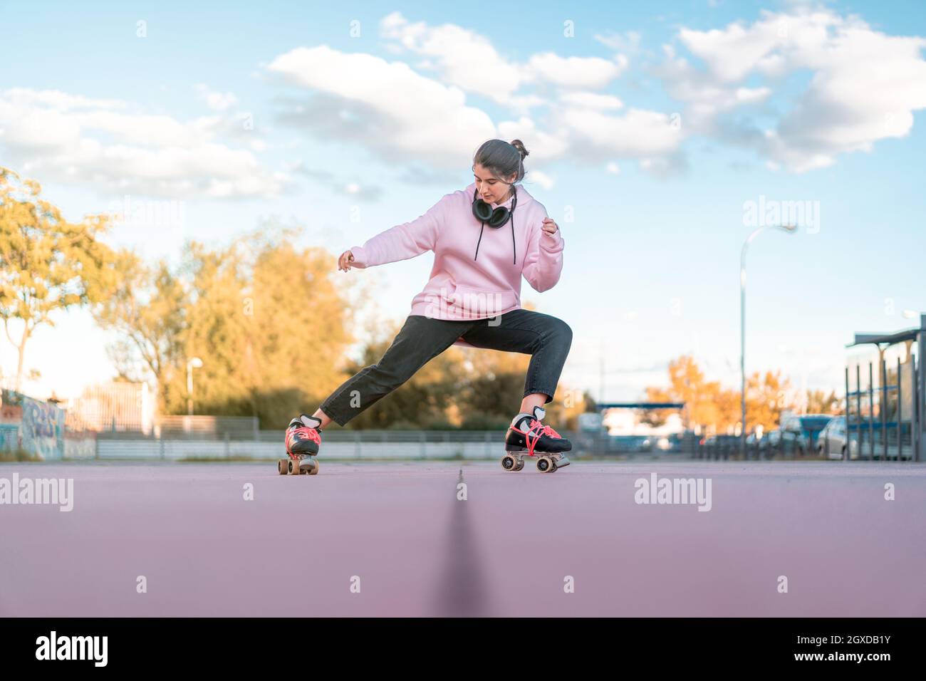 Full body of active young Woman skater wearing pink hoodie and black ...