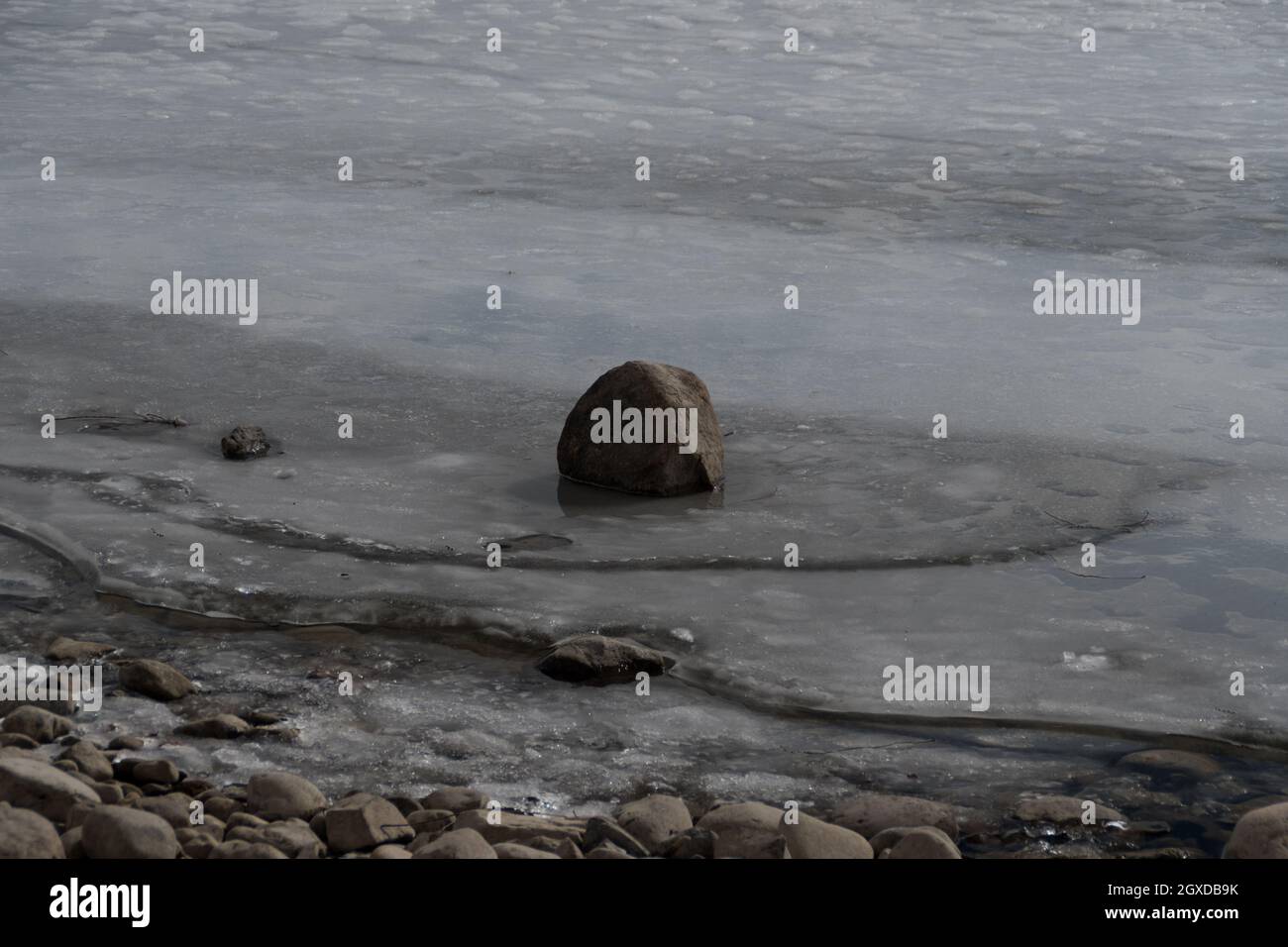Rock in frozen lake Stock Photo - Alamy