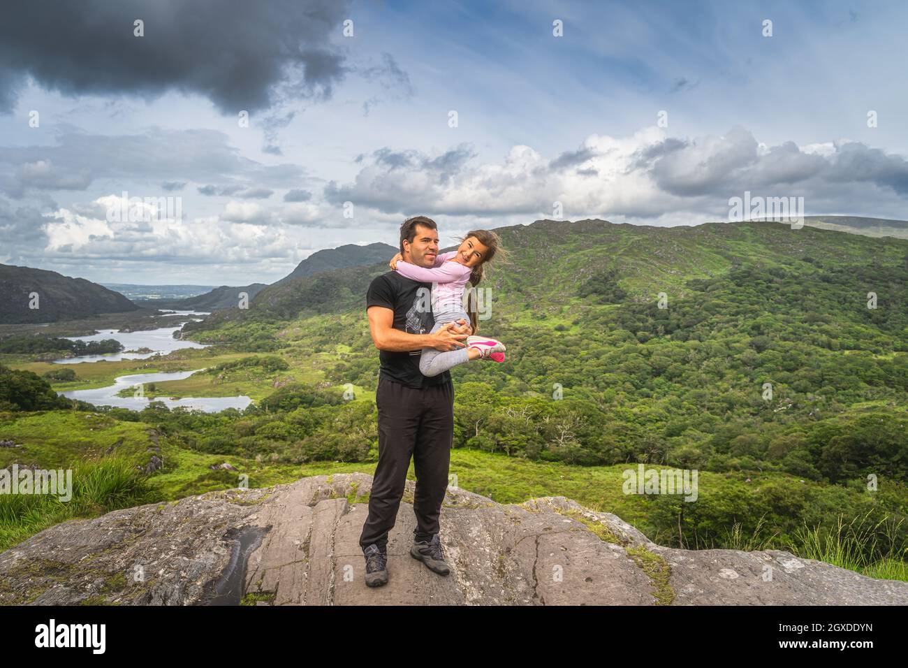 Father holding daughter on hands and standing on rock, enjoying ...