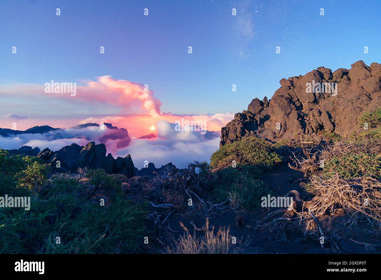 Night landscape with an erupting volcano in the background and a sea of ...