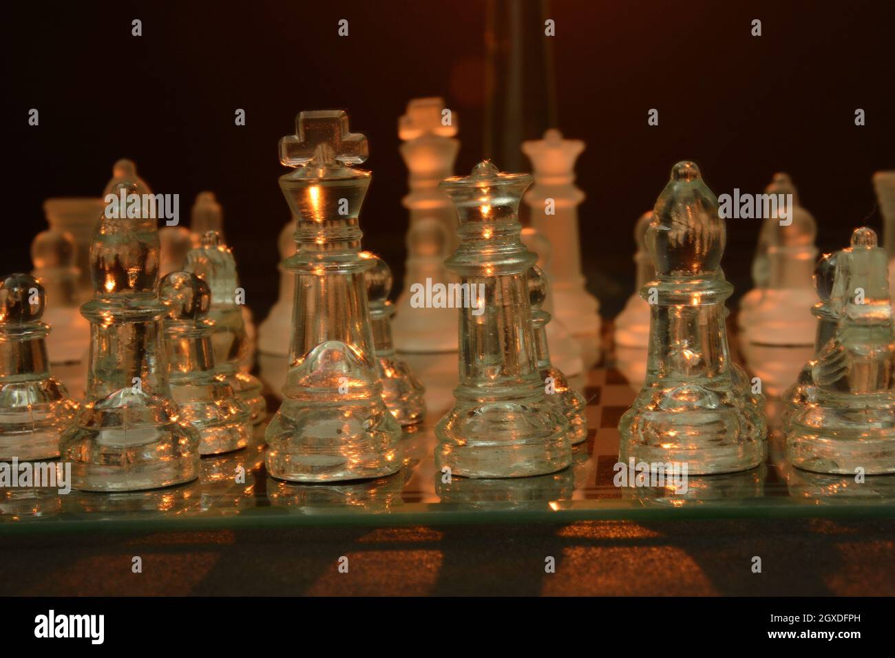 Clear glass chess pieces on a glass chessboard isolated on a black ...