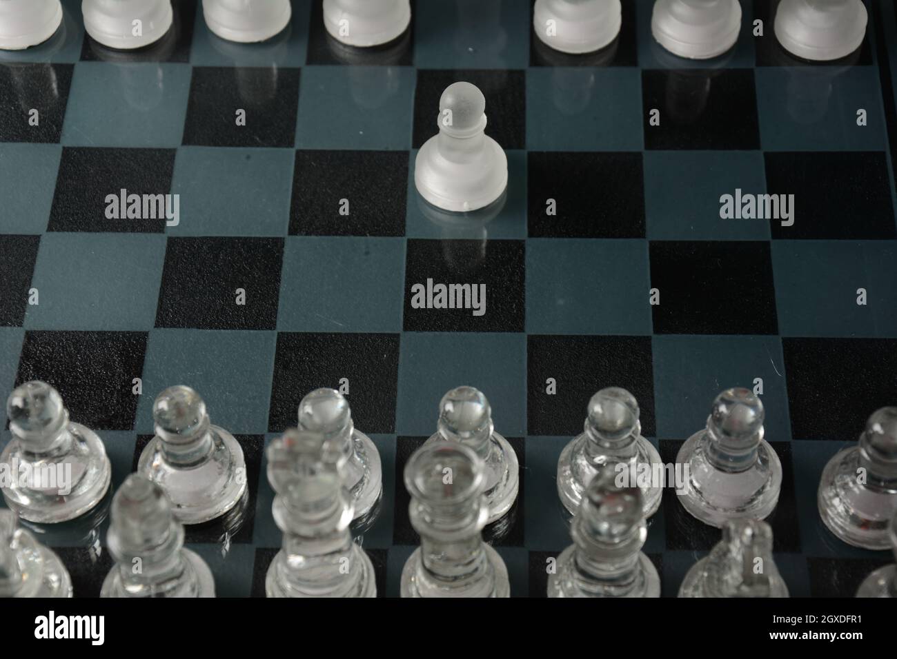 Clear glass chess pieces on a glass chessboard isolated on a black ...