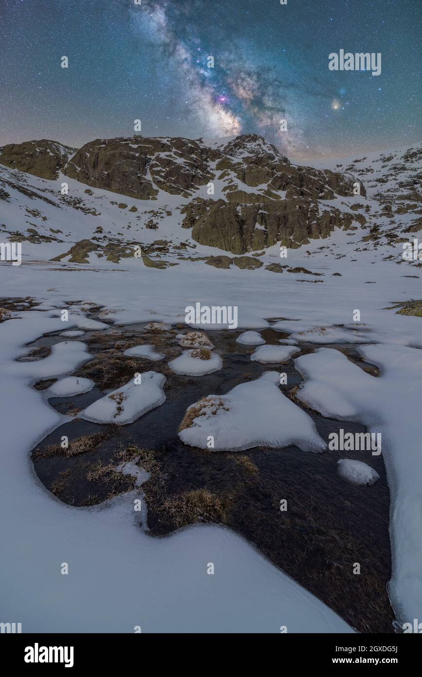 Landscape of puddle of ice water near mountain under night starry sky ...
