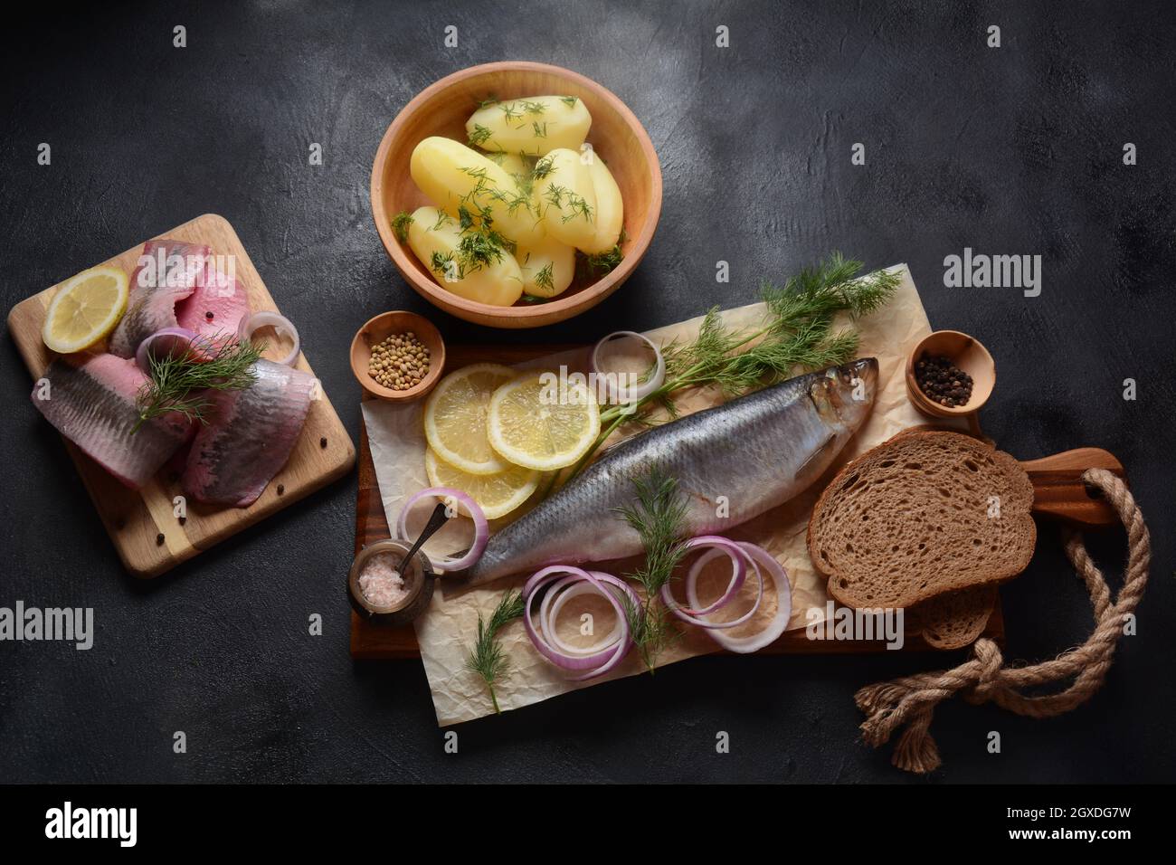 Herring fish on wooden board with pepper, herbs, red onion and lemon on ...