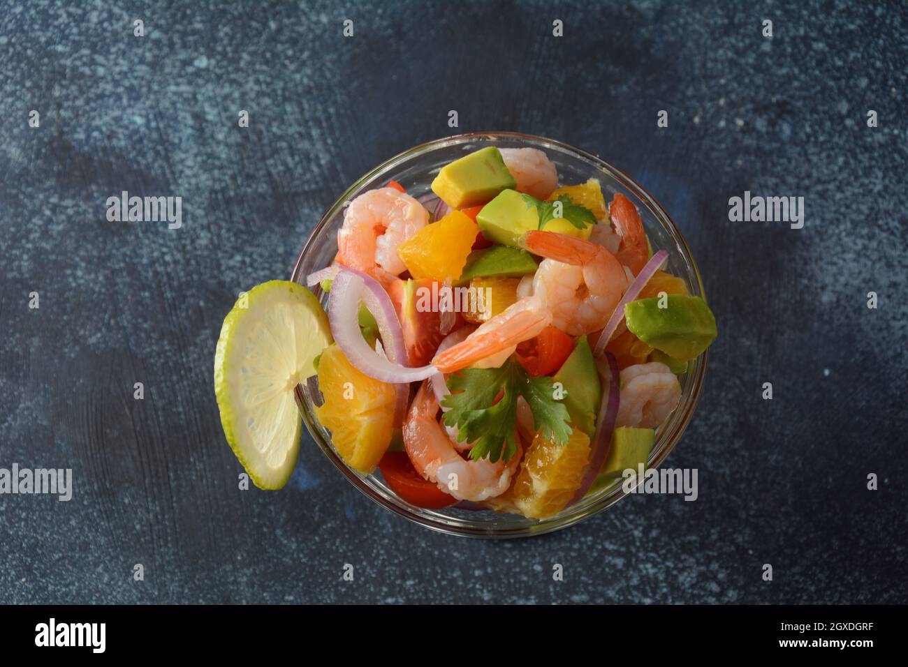 Ceviche salad with shrimps, oranges and avocado in glass bowl on a dark ...