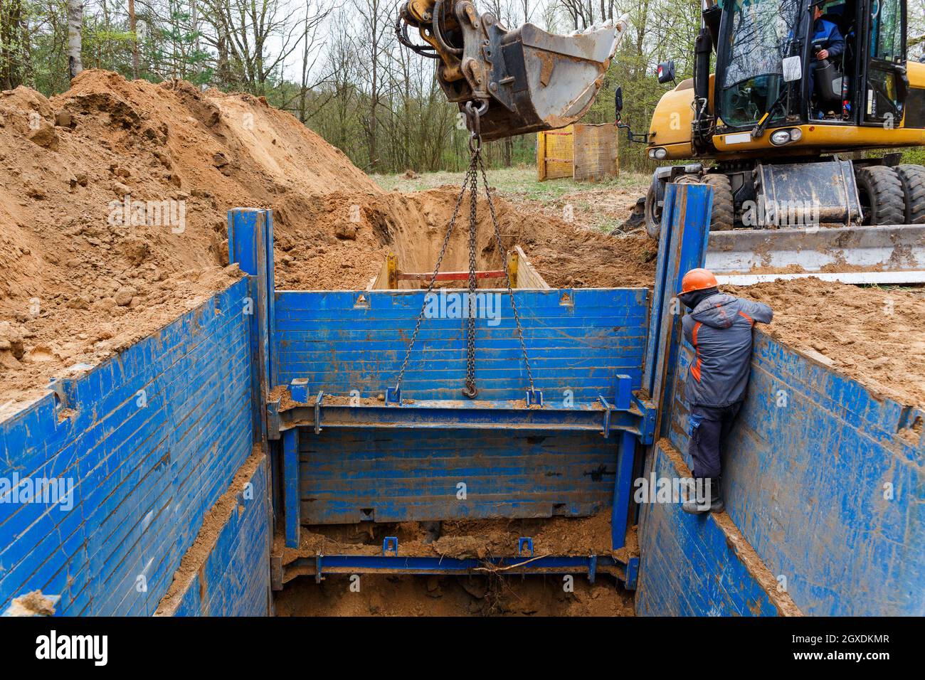 Installation of metal supports to protect the walls of the trench. The ...