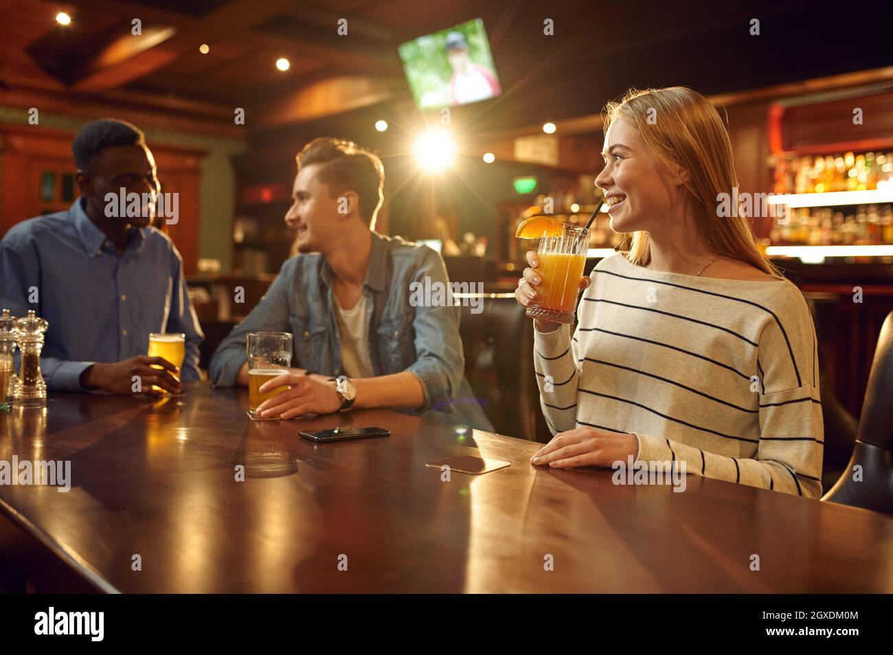 Three friends with alcohol beverages having fun at the table in bar ...
