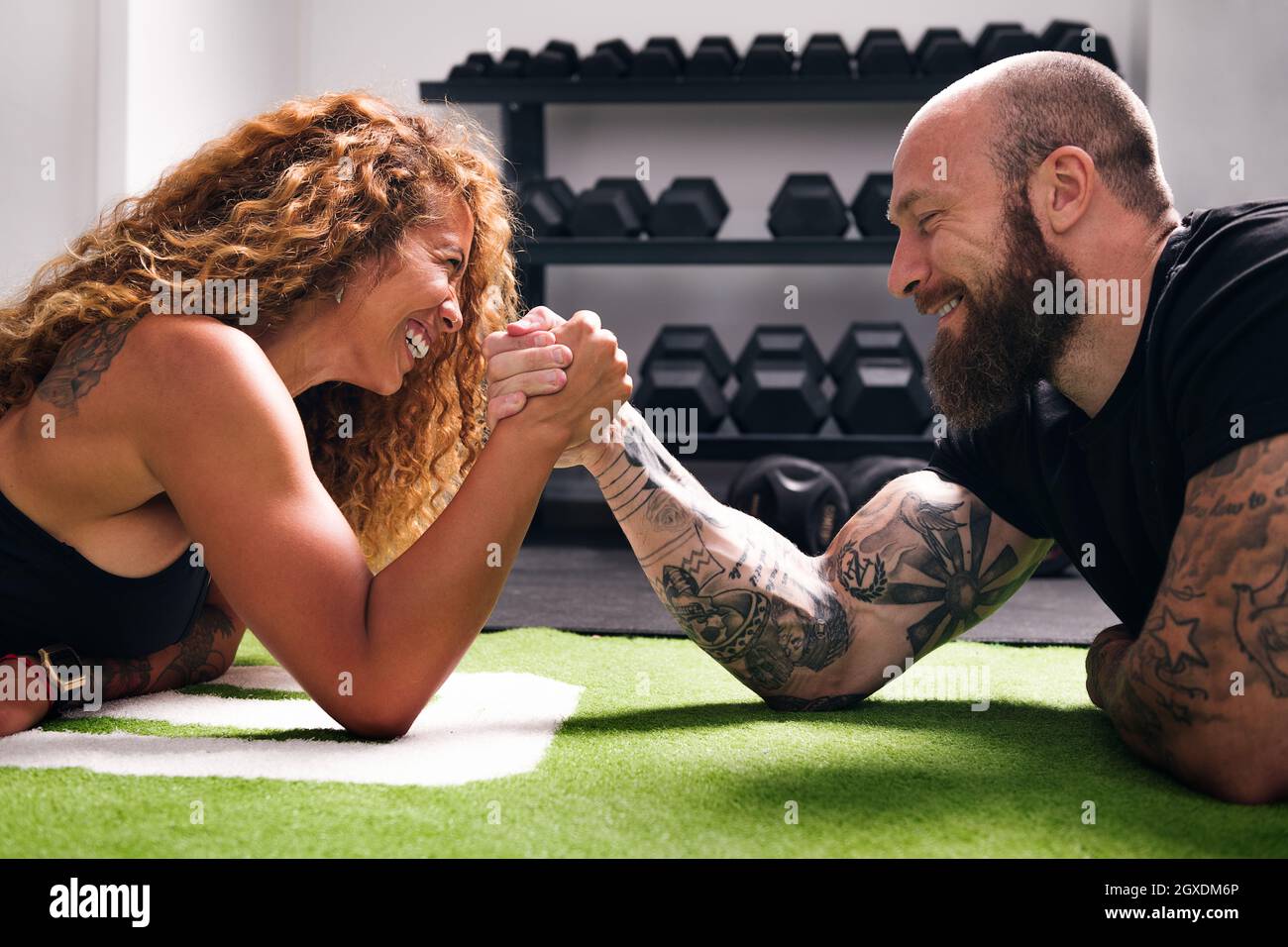 Side view of smiling hispanic sportsWoman with curly hair holding hand ...