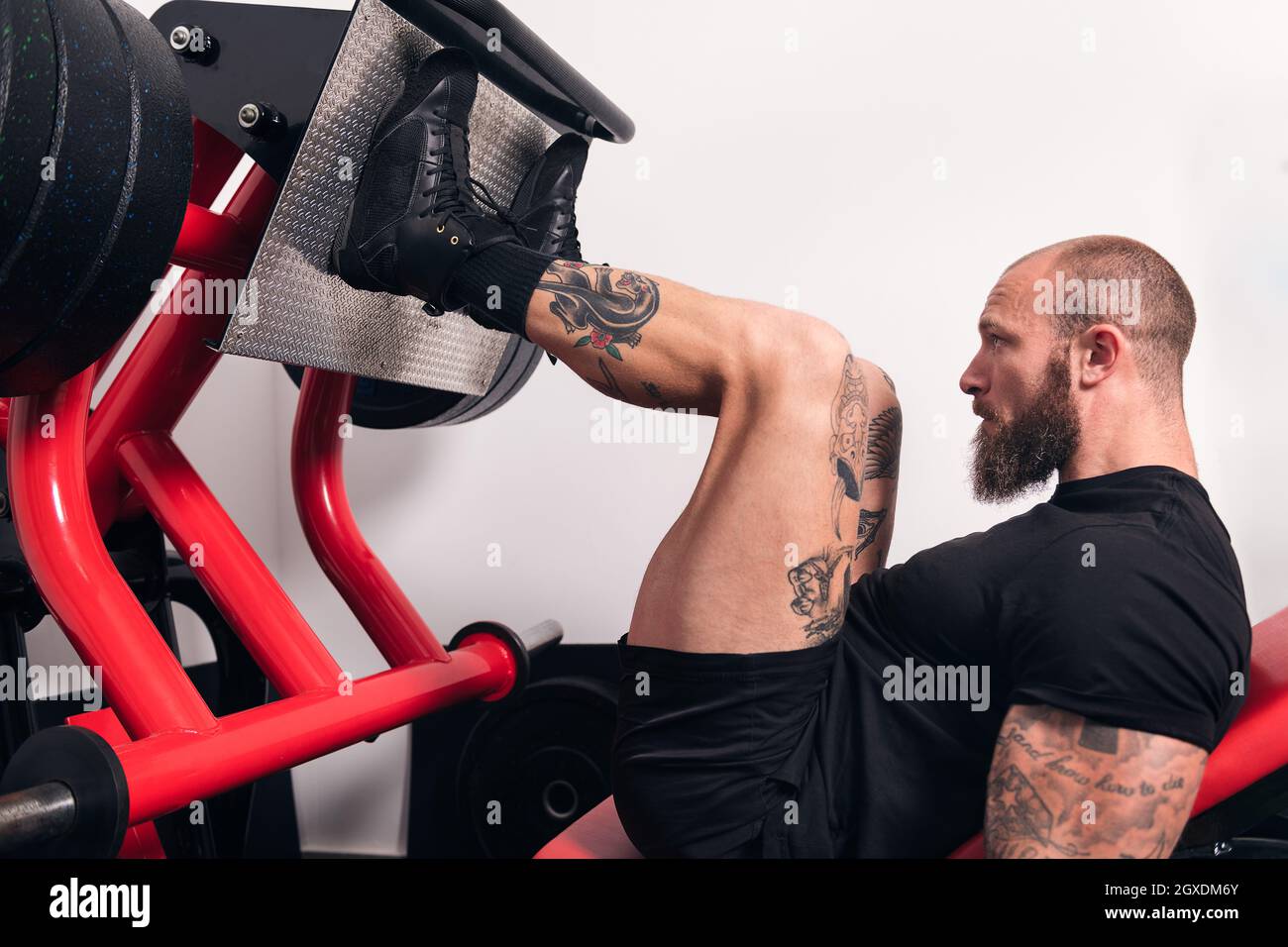 Side view of muscular sportsman with tattoos doing exercises on leg ...