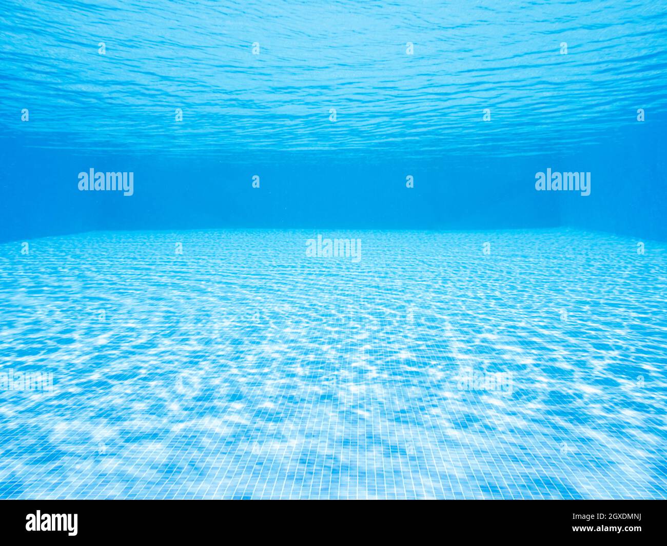 Blue swimming pool with glowing water with ripples above tiled bottom ...