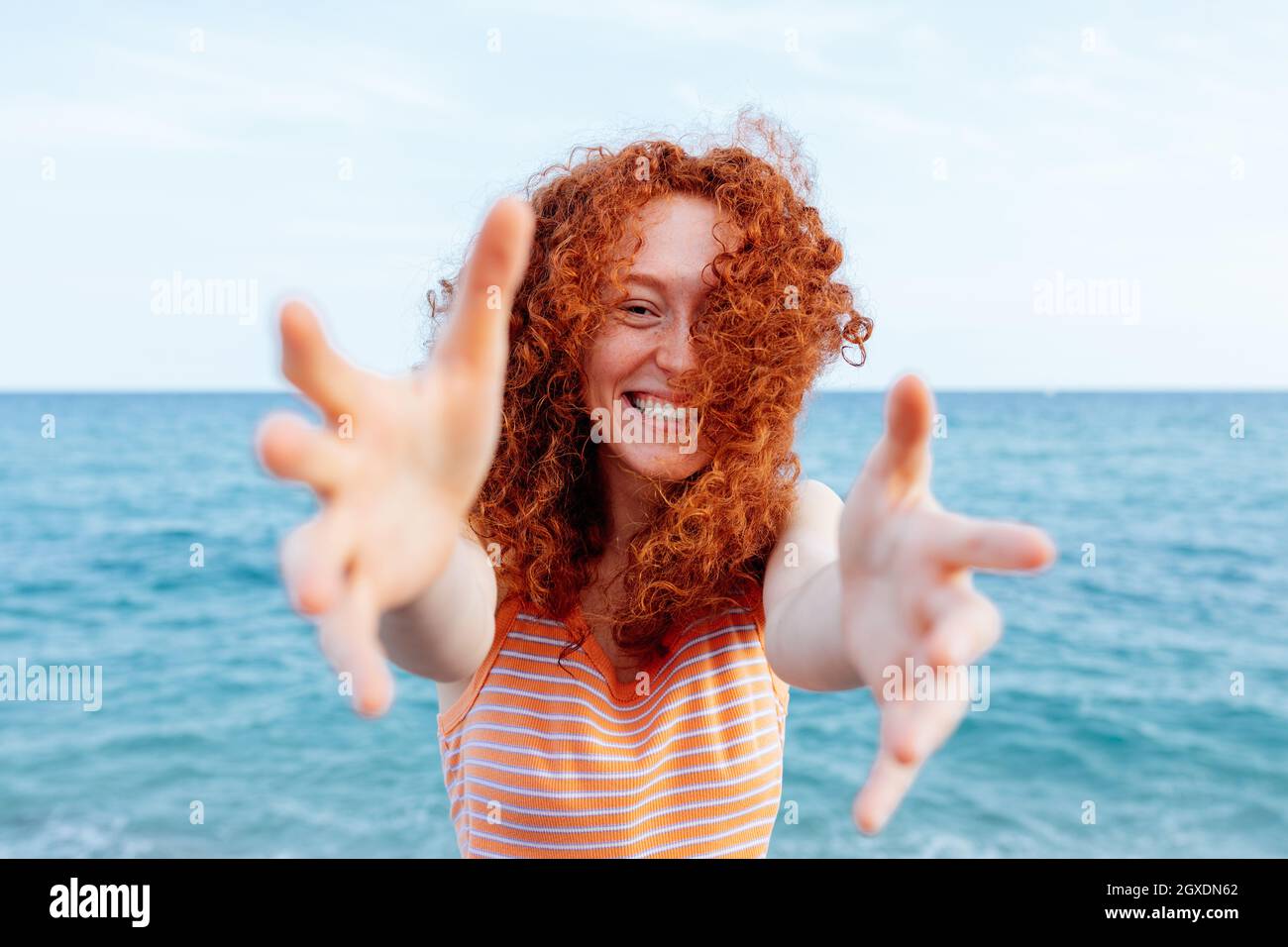 Optimistic young female with flying ginger hair reaching hands to ...