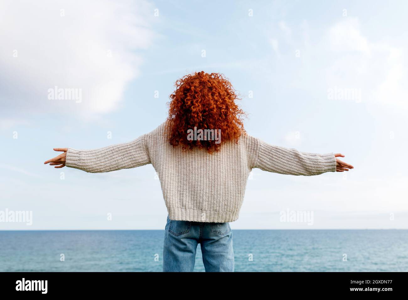 Back view of unrecognizable delighted female with curly long ginger ...