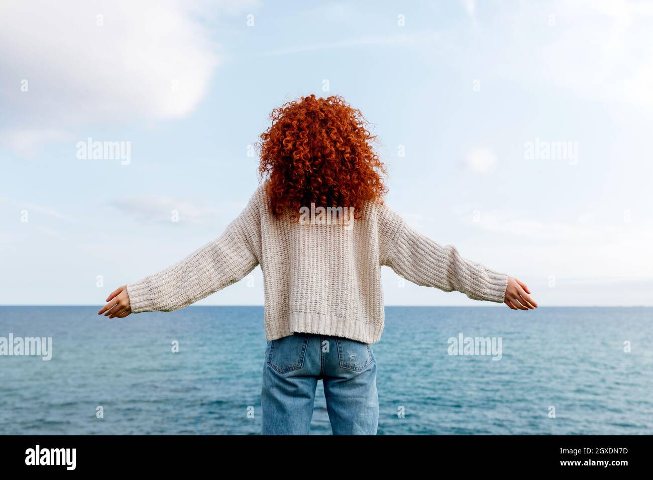Back view of unrecognizable delighted female with curly long ginger ...