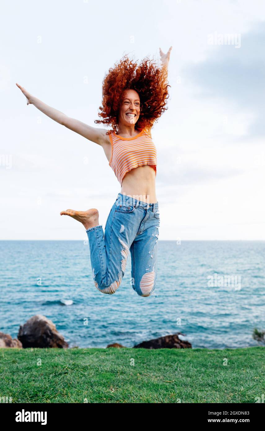 Full body of happy energetic female with flying ginger curly hair ...