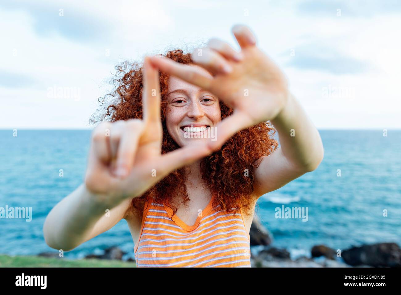 Positive female with long curly ginger hair shaping triangle on ...