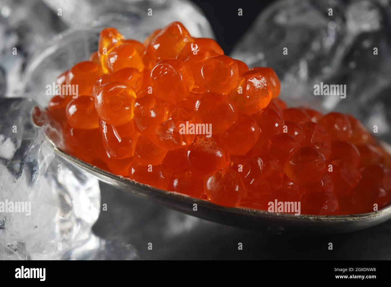 Red Caviar in a spoon on ice background. Close-up salmon caviar ...