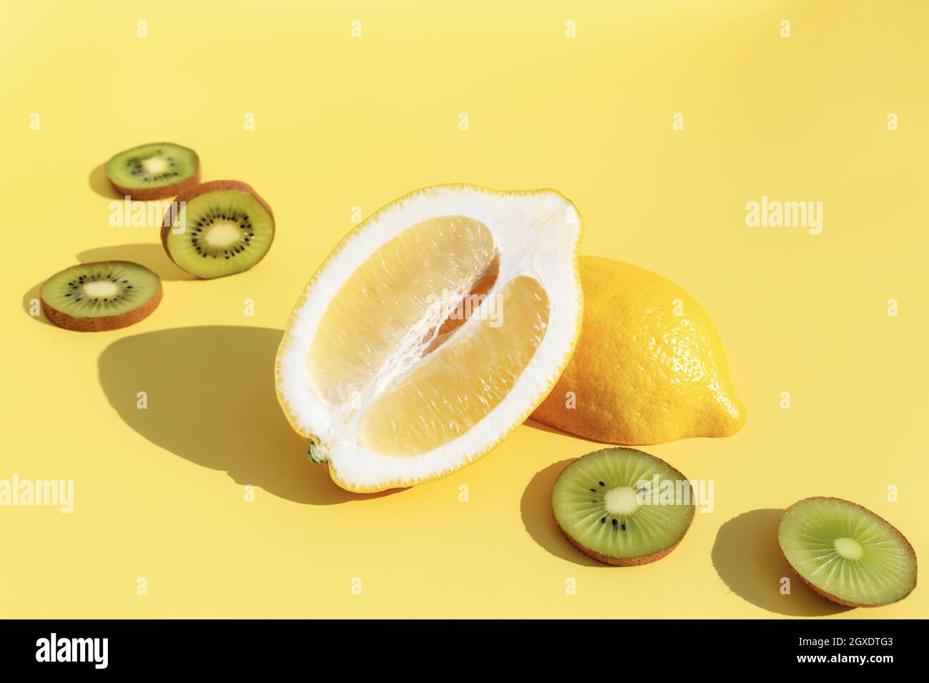 Halves of lemon with shadow, sliced kiwi cuts on yellow background ...