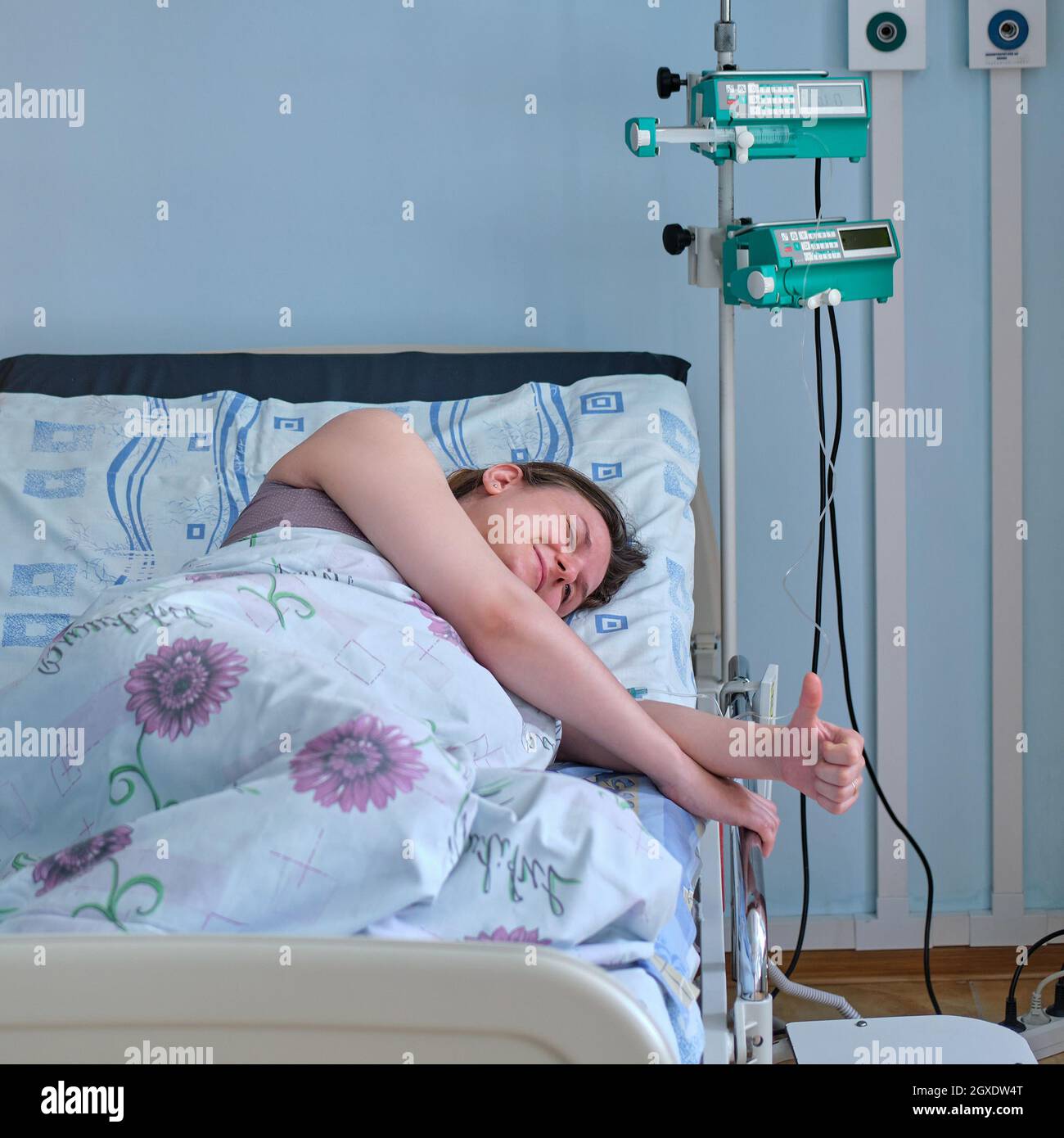Happy woman on clinic bed with anesthesia at the time of labor pains. A ...