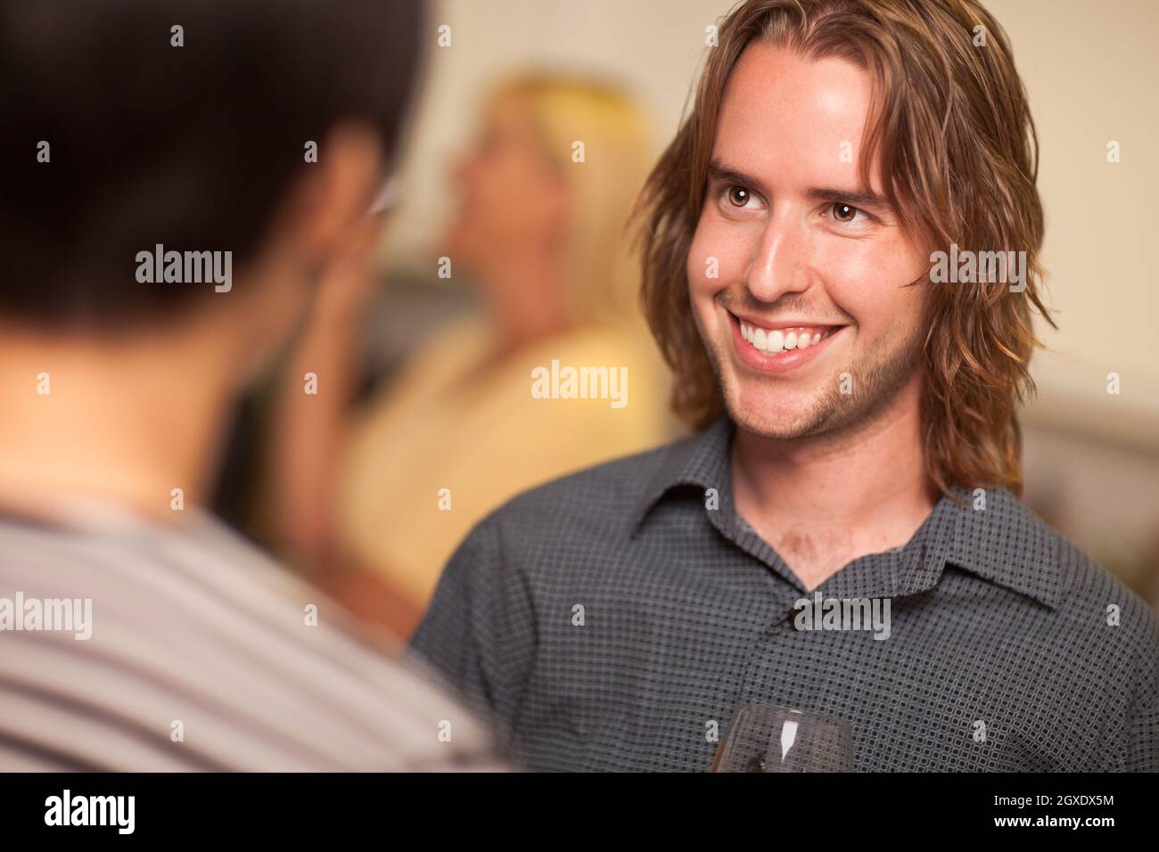 Smiling Young Man with Glass of Wine Socializing in a Party Setting ...