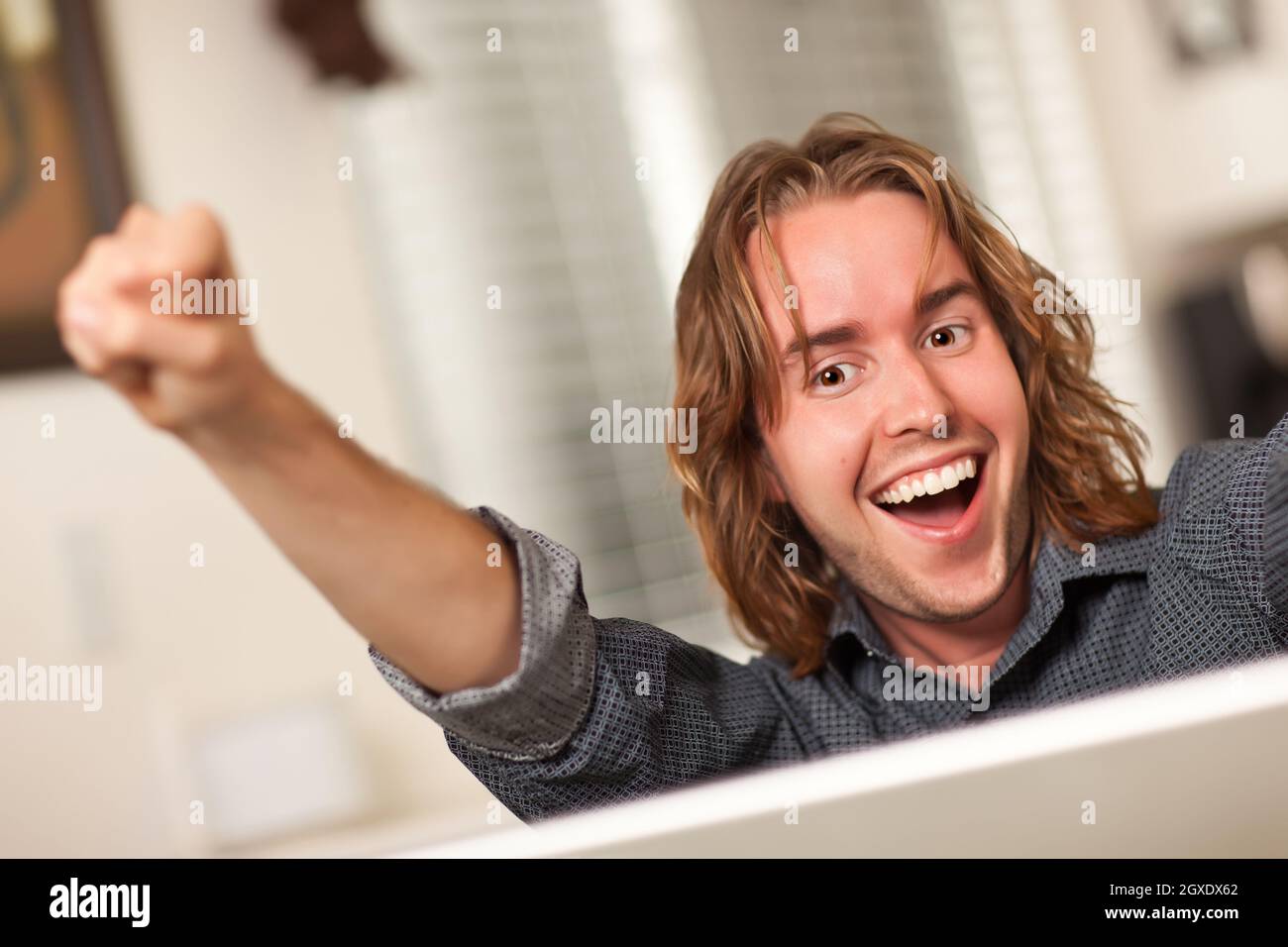 Happy Young Man Using A Laptop Computer and Cheering with Fists in the ...