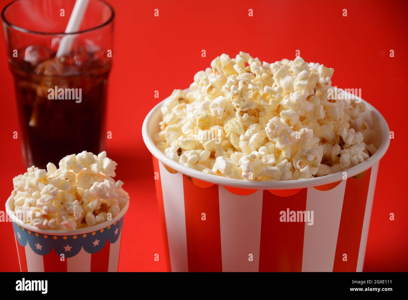 Buckets with delicious popcorn on red background and a glass of Coca ...