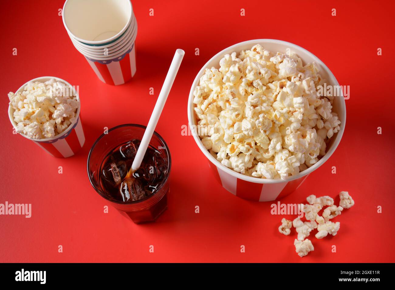 Buckets with delicious popcorn on red background and a glass of Coca ...