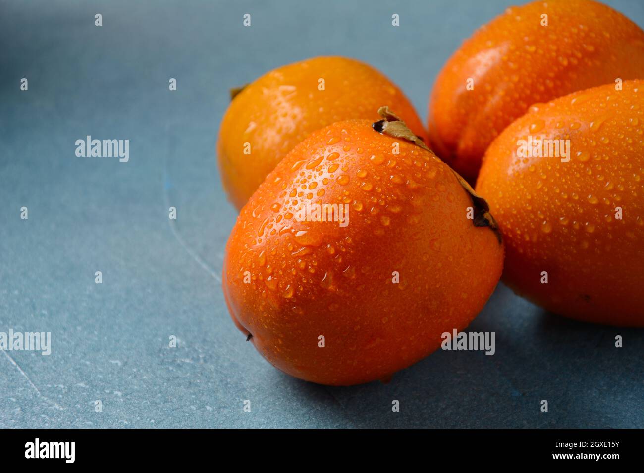 Three ripe persimmons on a blue background. Delicious fresh persimmon ...
