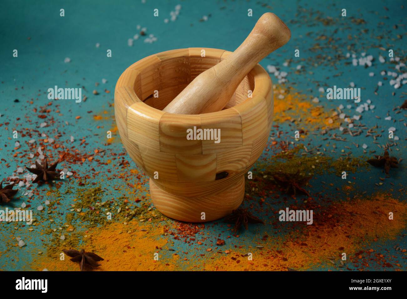 Wooden spice mortar and spices on blue background Stock Photo - Alamy