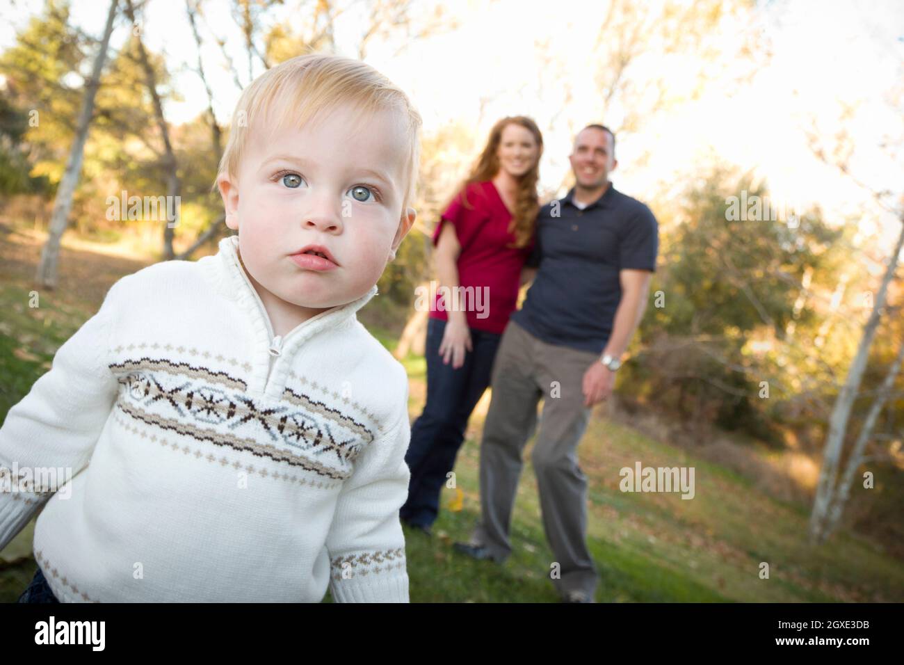 Cute Young Boy Walking in the park as Adoring Parents Look On From ...