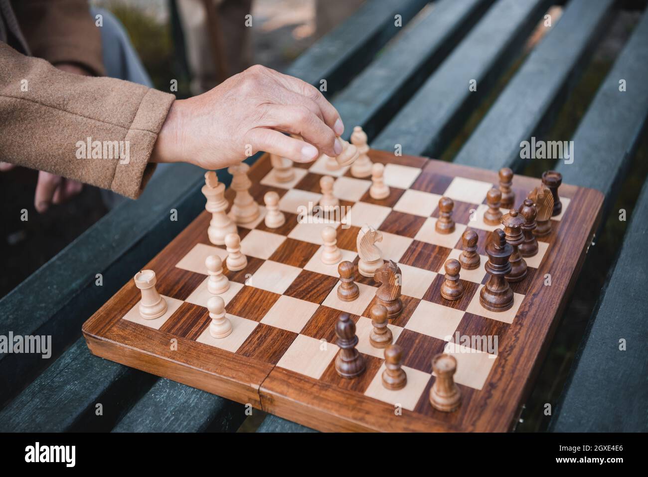 Cropped view of senior man playing chess on bench in park Stock Photo ...
