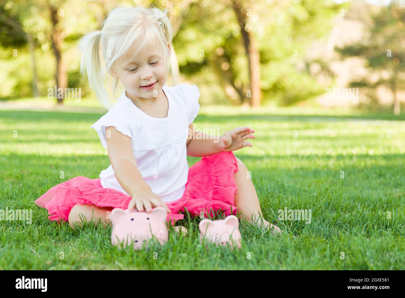 Cute Little Girl Having Fun with Her Large and Small Piggy Banks ...