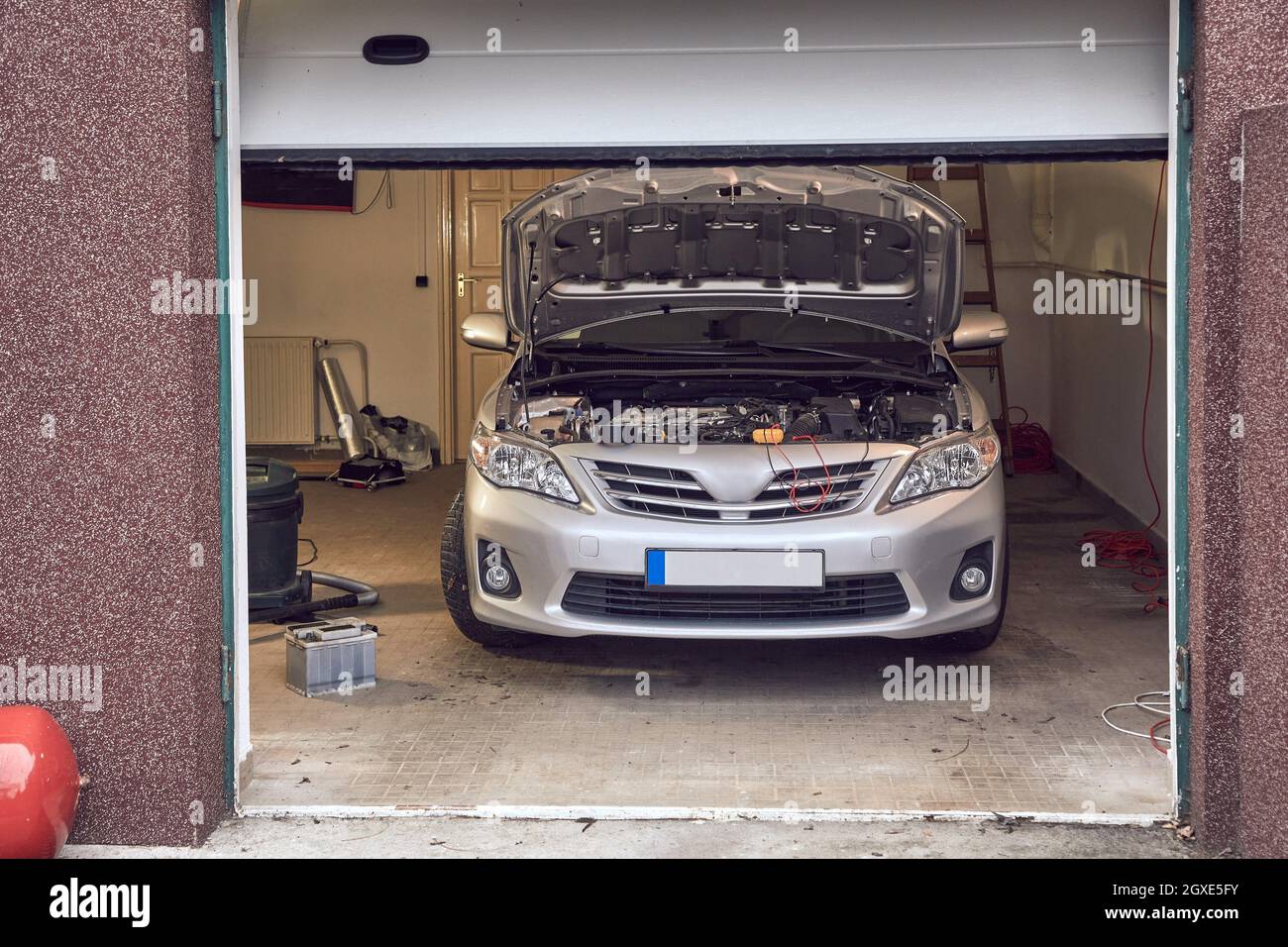 Car in a small repair shop garage with open hood, engine diagnostics ...