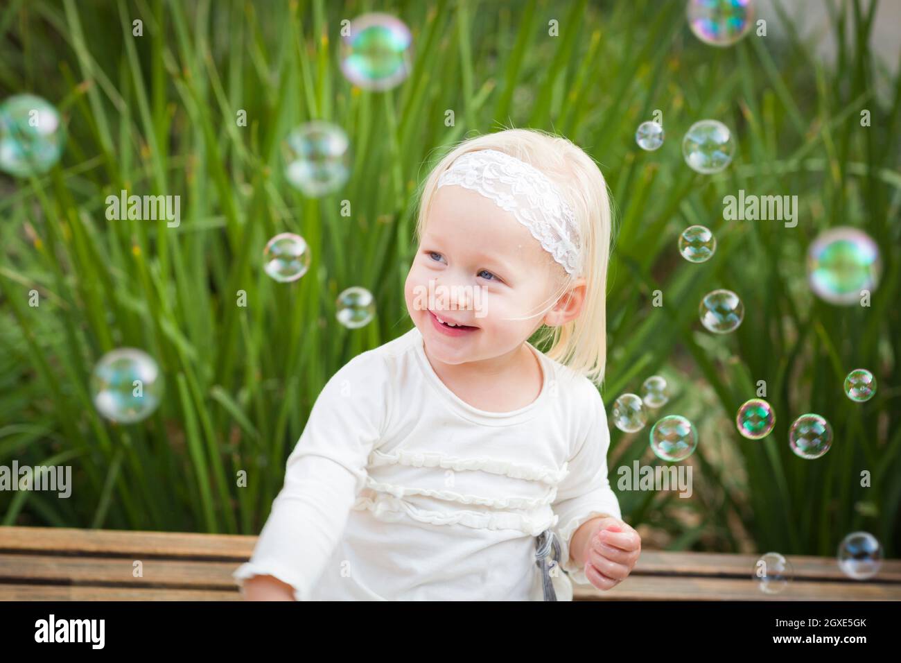 Adorable Little Girl Sitting On Bench Having Fun With Bubbles Outside Stock Photo - Alamy