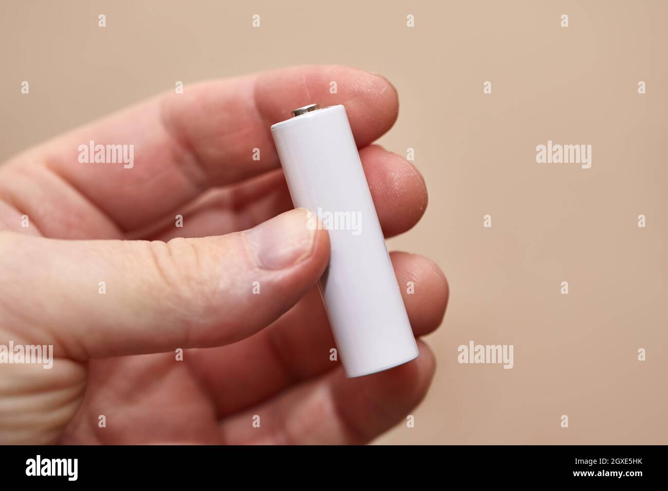 AA Battery Cell held in hand, blank white surface Stock Photo - Alamy