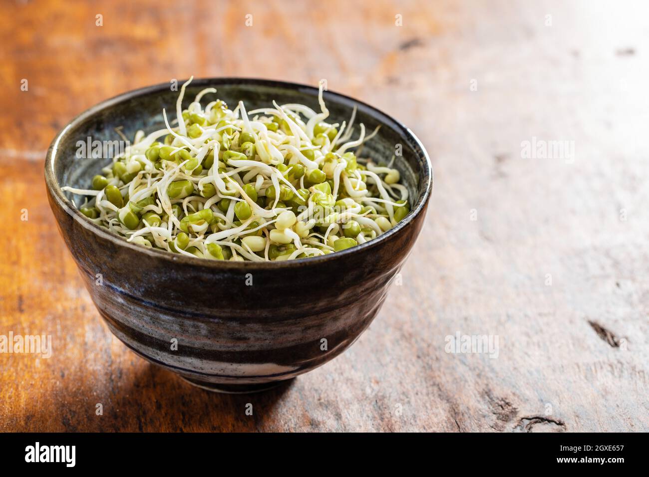 Sprouted green mung beans. Mung sprouts in bowl on wooden table Stock ...