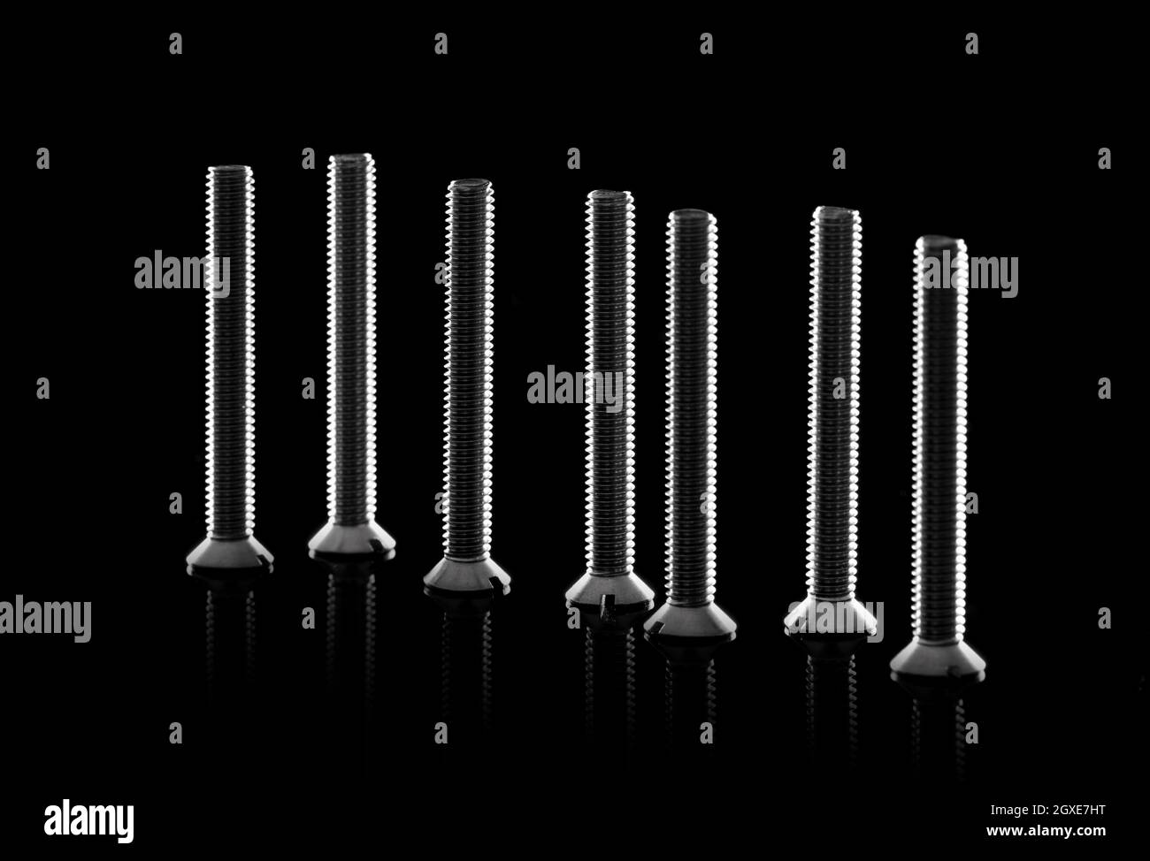 Chrome screws in a line on black Stock Photo - Alamy