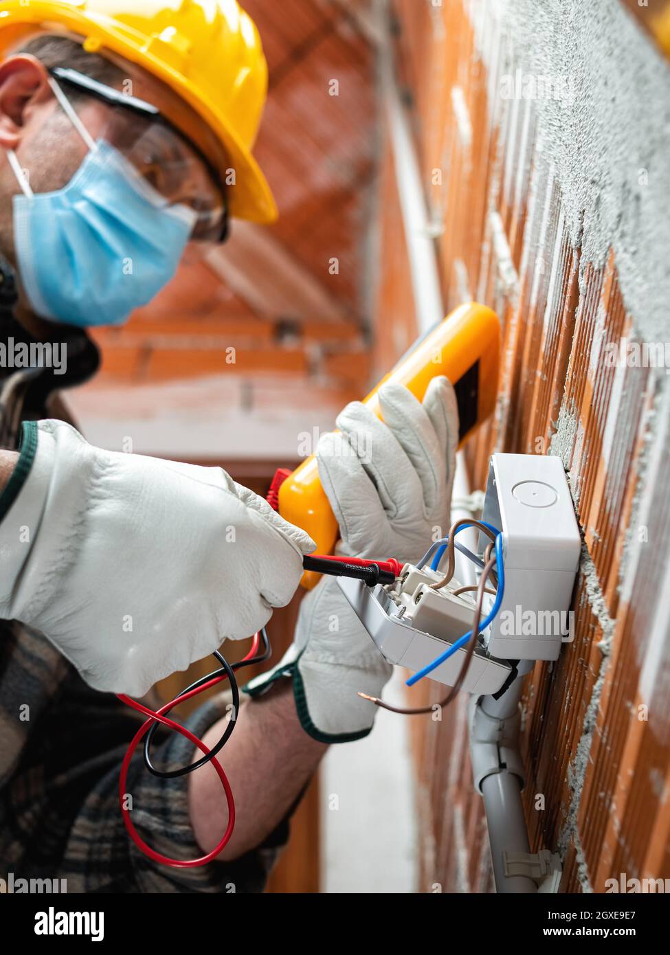 Electrician worker with tester measures the voltage in an electrical ...
