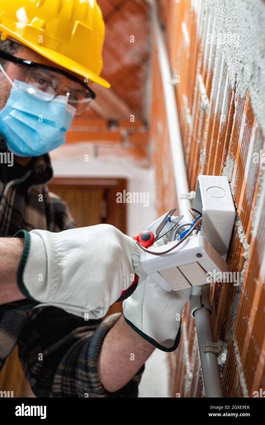 Electrician worker with scissors prepares the electrical cables of an ...