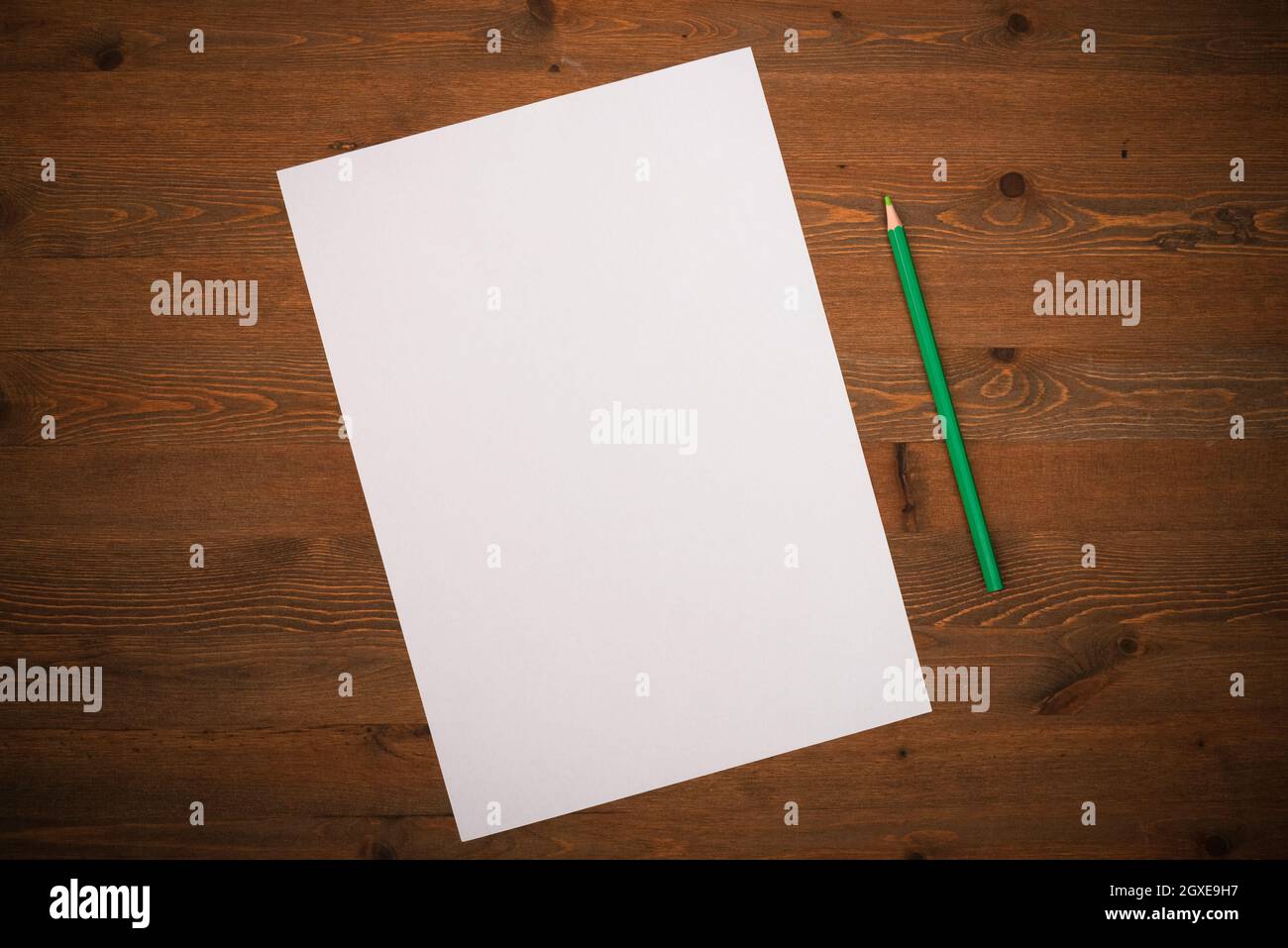 A blank white sheet and pencil for drawing on a wooden background with ...