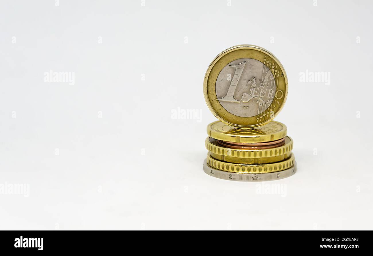 Various euro coins stacked with one euro coin standing on top. Coins ...