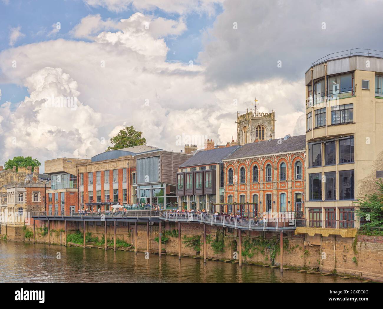 Buildings on a river bank with a sloping terrace. A church tower rises ...
