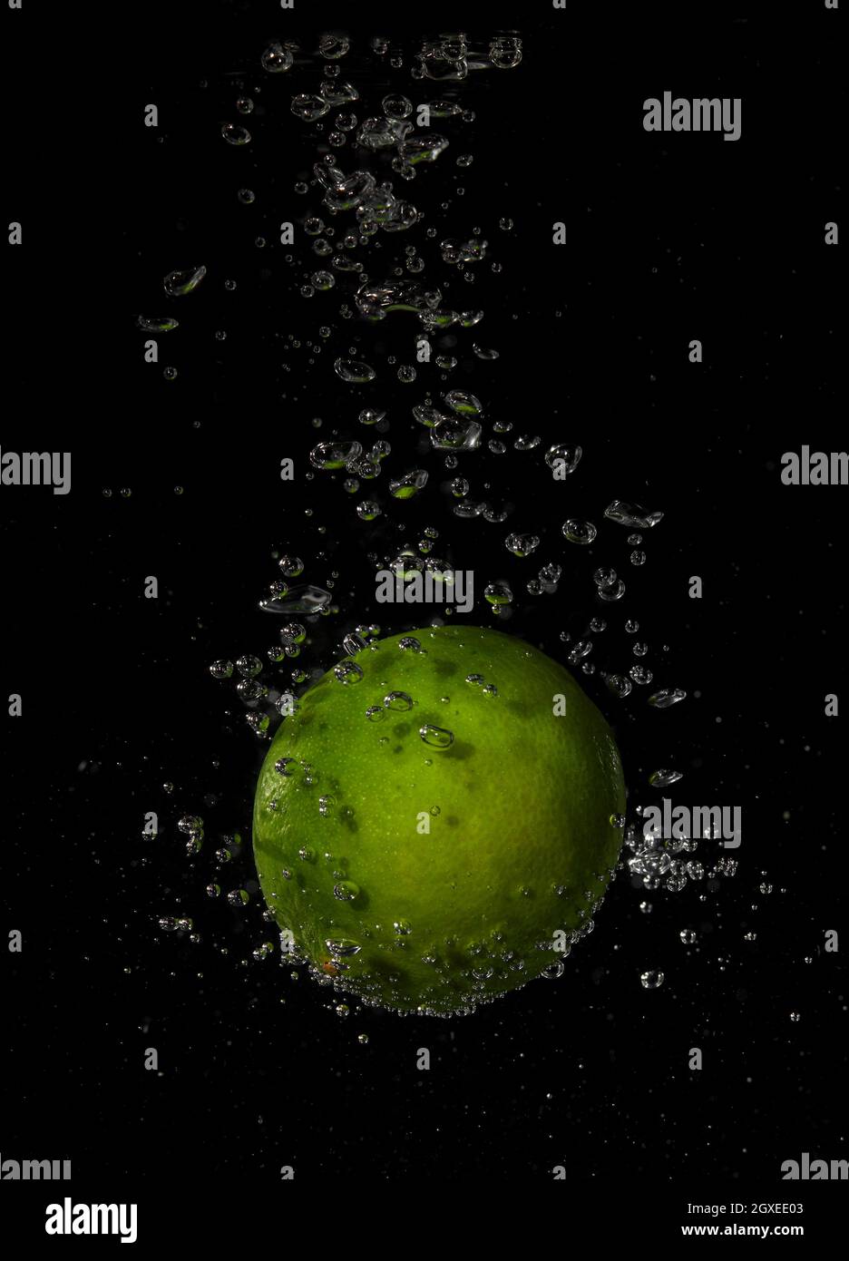Lime splashing in water on a black background Stock Photo - Alamy